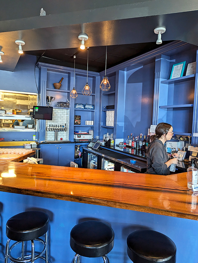 The warm wood bar top contrasts beautifully with cool blue surroundings. Those pendant lights aren't just illuminating space&mdash;they're spotlighting your next great meal.