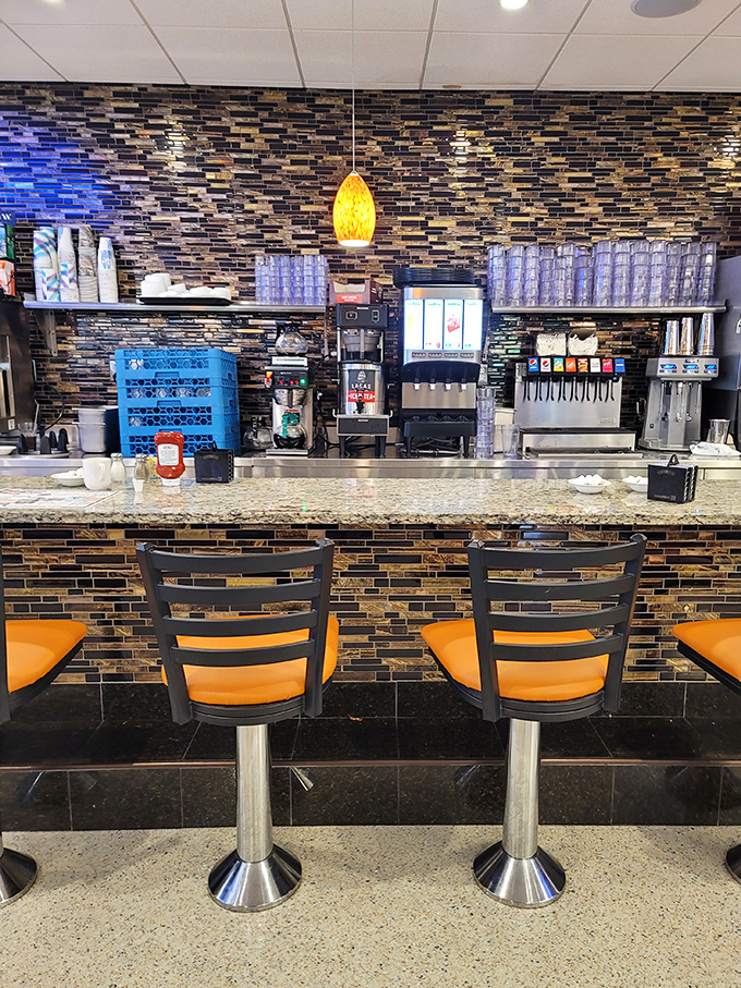 The bar stools aren't just seating—they're front-row tickets to the breakfast show. Those orange cushions have witnessed countless coffee refills and life stories.