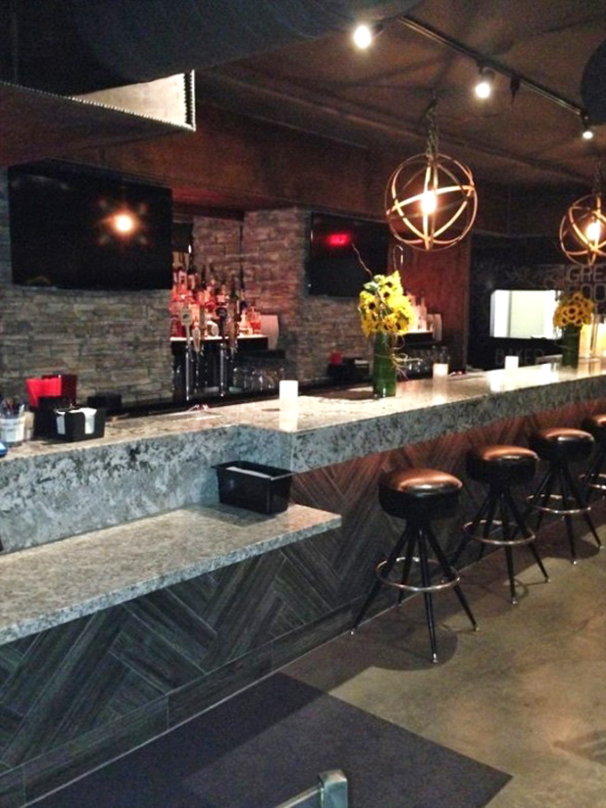 The bar isn't just serving drinks&mdash;it's crafting liquid companions for your smoked meat journey under warm, globe-shaped lighting. 