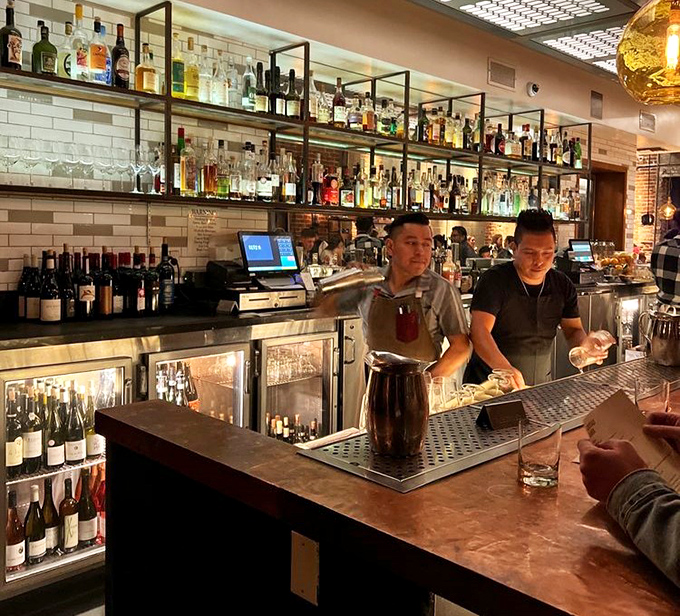 Bartenders orchestrating liquid happiness behind a bar stocked with enough spirits to raise the dead or at least your spirits.