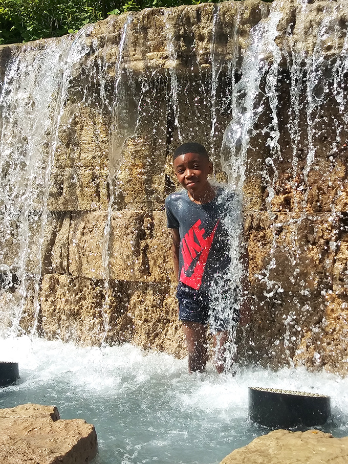 Citygarden's waterfall wall becomes summer's favorite cooling station. Pure joy captured as refreshing cascades provide the ultimate urban oasis experience.