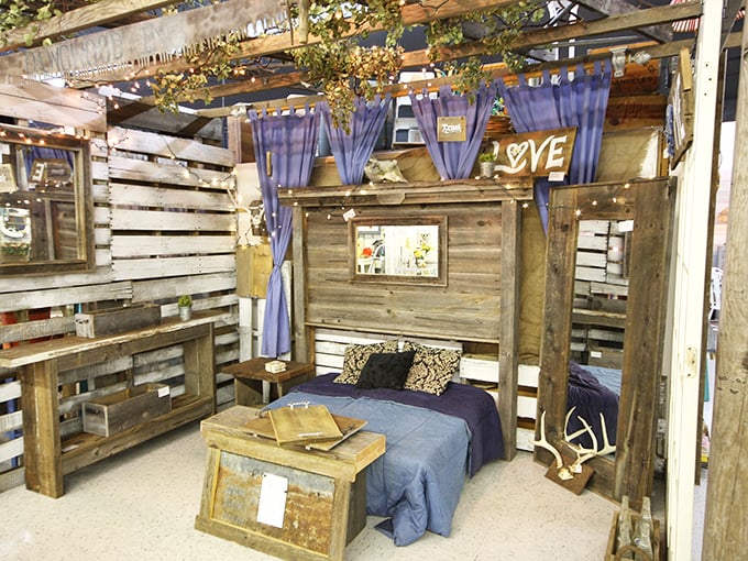 Rustic romance comes alive in this pallet bed display. Proof that reclaimed wood and purple linens are a match made in design heaven.