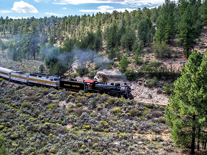 The vintage locomotive navigates curves through Arizona's rugged terrain, a black iron serpent winding through a landscape unchanged for centuries.
