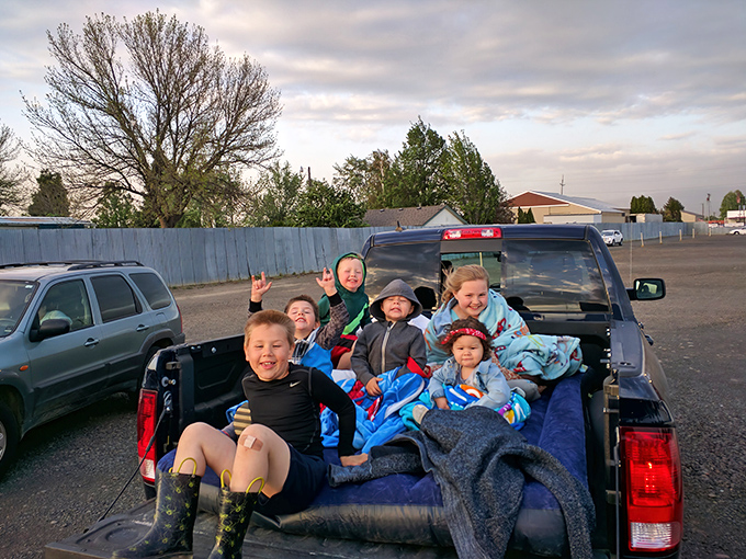 The truck bed becomes the ultimate luxury box for these young movie critics, complete with blanket fort potential and unlimited wiggle room.