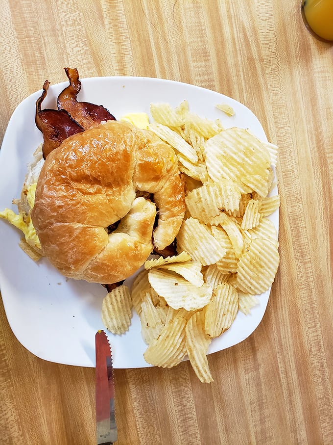 Breakfast sandwich perfection: the flaky croissant, the hint of bacon peeking out, the chips standing by. Morning fuel has never looked so inviting.