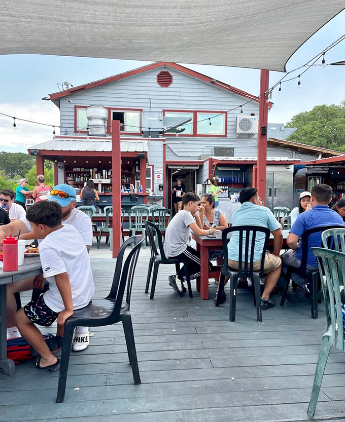 Happy diners gathering around tables where good food creates instant friendships and lasting coastal memories together.
