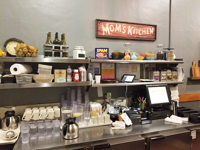 The "Mom's Kitchen" sign says it all &ndash; this is comfort food territory. The organized chaos of a working kitchen where magic happens daily. 