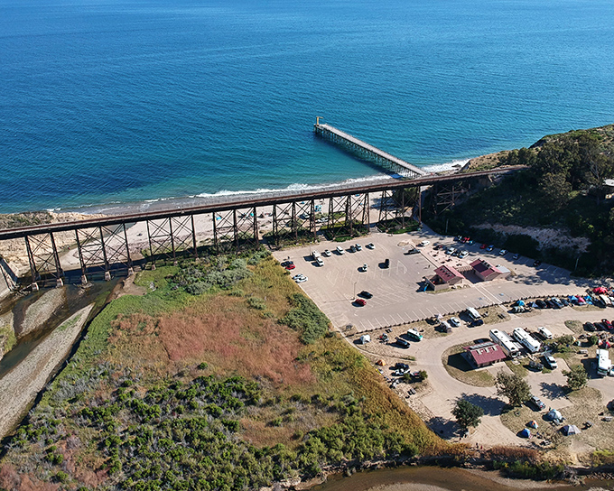 The ultimate panorama where railroad trestle meets pristine beach&mdash;proof that sometimes industrial and natural beauty can coexist like old friends.
