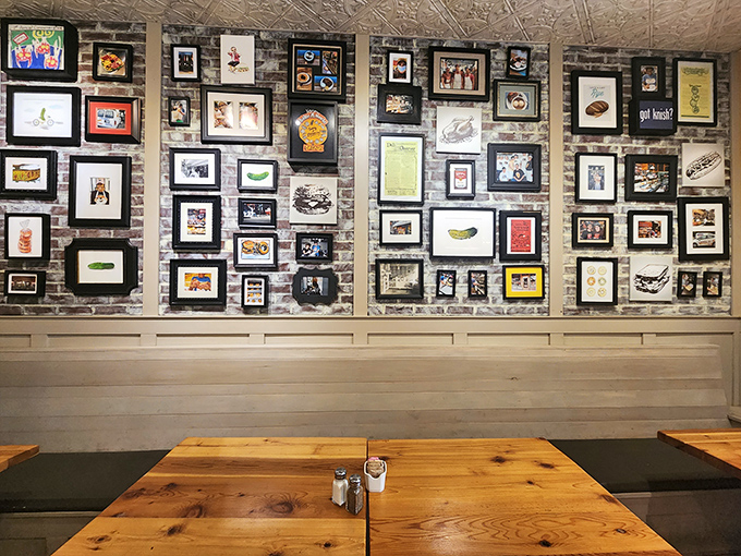 The wall of framed art isn't just decoration&mdash;it's a visual history of deli culture and sandwich appreciation. Each frame tells a story of culinary devotion.