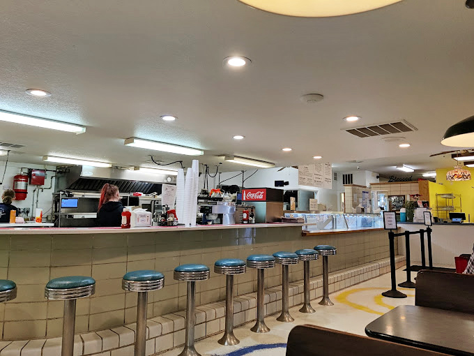 The classic diner counter setup invites solo diners to perch on chrome stools for front-row views of short-order magic.