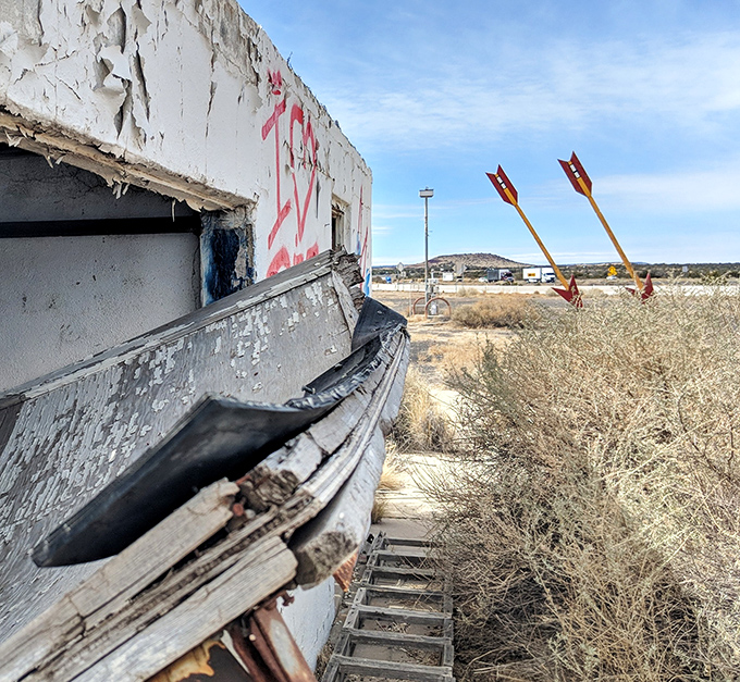 The weathered trading post walls frame a perfect view of the arrows, like an accidental art installation celebrating American mobility.