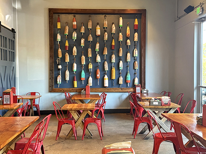 The wall of colorful buoys isn't just decoration—it's maritime art. Those red metal chairs say "sit down and prepare for something memorable."