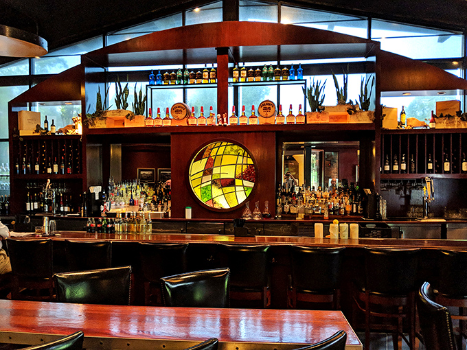 The bar area gleams with amber bottles and warm wood tones&mdash;a liquid library of spirits waiting to complement your meal.