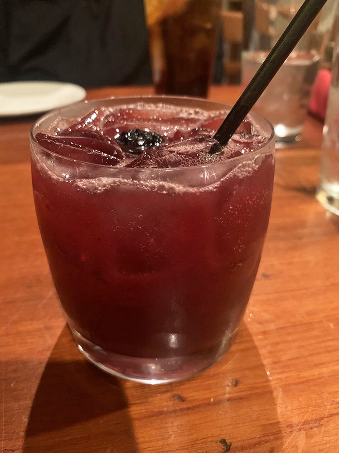 A cocktail the color of sunset, promising vacation vibes regardless of your PTO status. That blackberry isn't just garnish&mdash;it's the exclamation point on liquid relaxation.