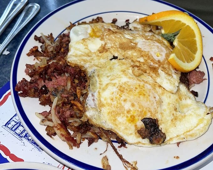 Breakfast of champions: eggs lounging comfortably next to corned beef hash. The orange slice is just there to make you feel virtuous.