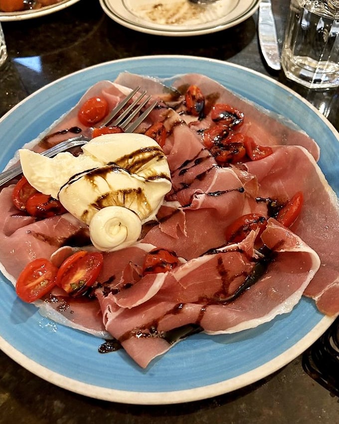 Prosciutto arranged like silk ribbons, with cherry tomatoes and mozzarella playing the perfect supporting roles. Italy on a blue plate.