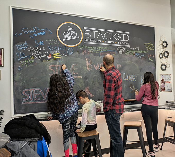 The community chalkboard where customers become artists, leaving their mark in a colorful testament to burger joy.
