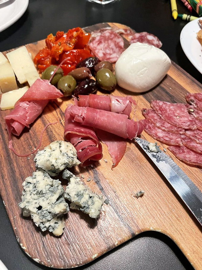 A charcuterie board that's basically a United Nations of cured meats, cheeses, and olives negotiating delicious peace on a wooden platform.