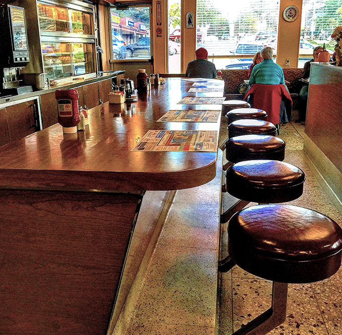 Copper pendant lights illuminate the heart of diner operations, where orders appear and breakfast dreams become delicious reality.