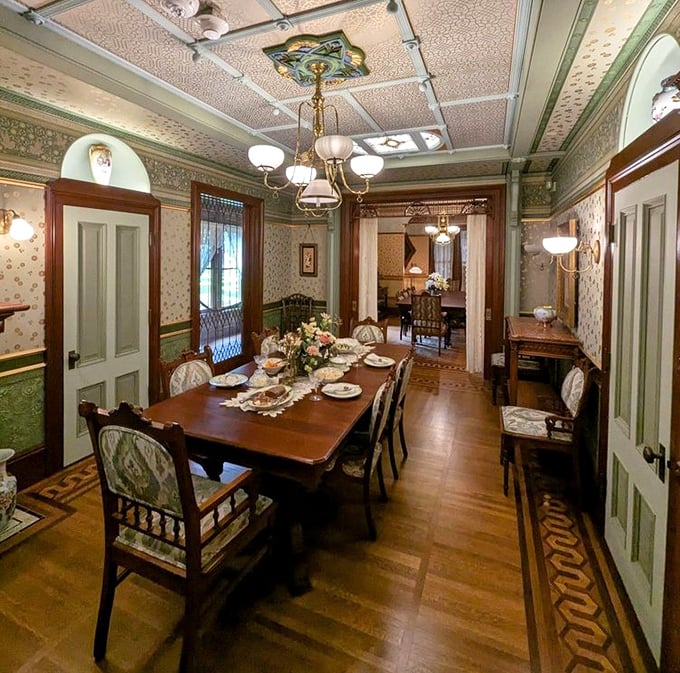 The formal dining room stands ready for ghostly dinner guests, its wallpapered elegance and ornate ceiling a testament to Victorian opulence.