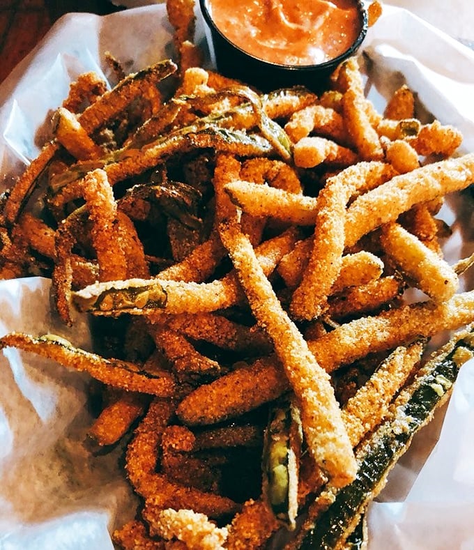 Fried pickles that crunch louder than your dad's knees at a family picnic, dusted with cornmeal and served with a dipping sauce worth bottling.