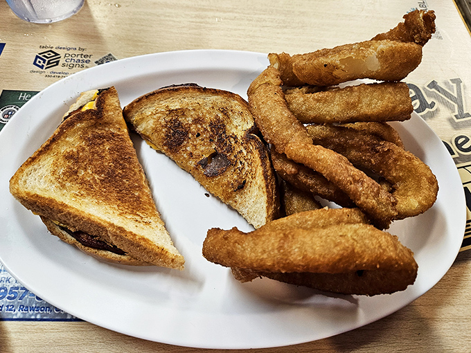 Golden-brown grilled sandwich triangles with perfectly melted cheese flanked by onion rings that shatter satisfyingly with each bite.