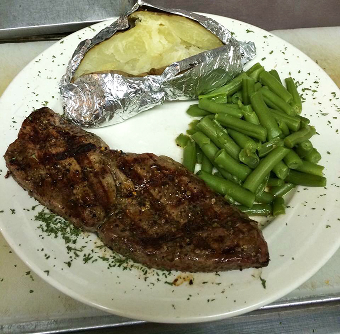 A steak that knows exactly what it's doing, accompanied by a baked potato in formal attire and green beans that actually look worth eating.