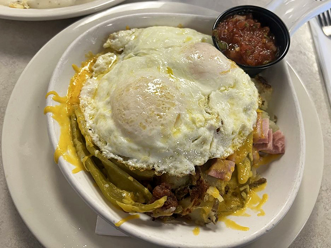 Eggs perched majestically atop a mountain of hash browns, peppers, and ham&mdash;a breakfast Everest worth conquering one delicious bite at a time.