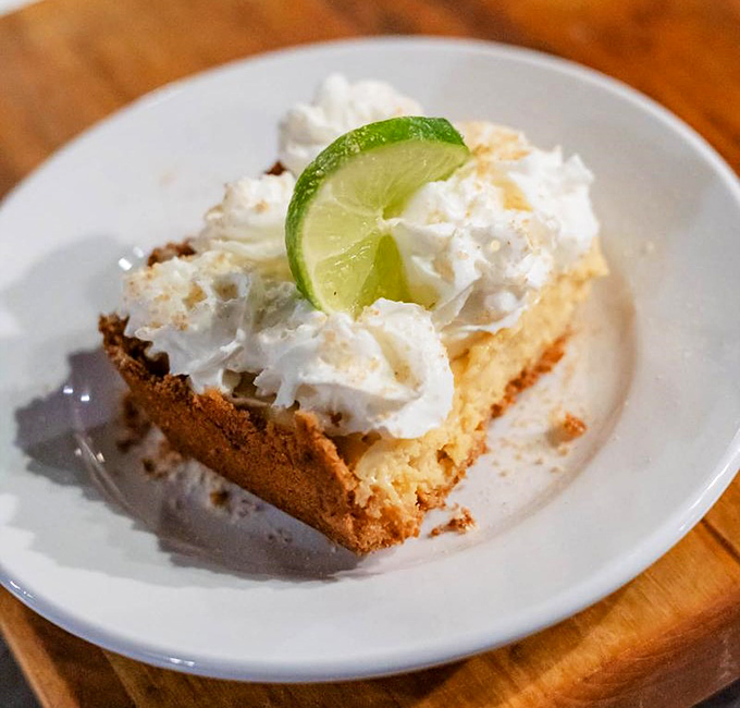 Key lime pie that strikes that impossible balance between tart and sweet, topped with a cloud of whipped cream and a lime slice winking at you.