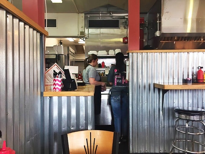 The open kitchen buzzes with activity as skilled cooks transform fresh ingredients into comfort food masterpieces.