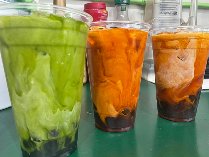 Three milk teas standing like colorful soldiers&mdash;green, orange, and caramel&mdash;each promising a different path to refreshment heaven.