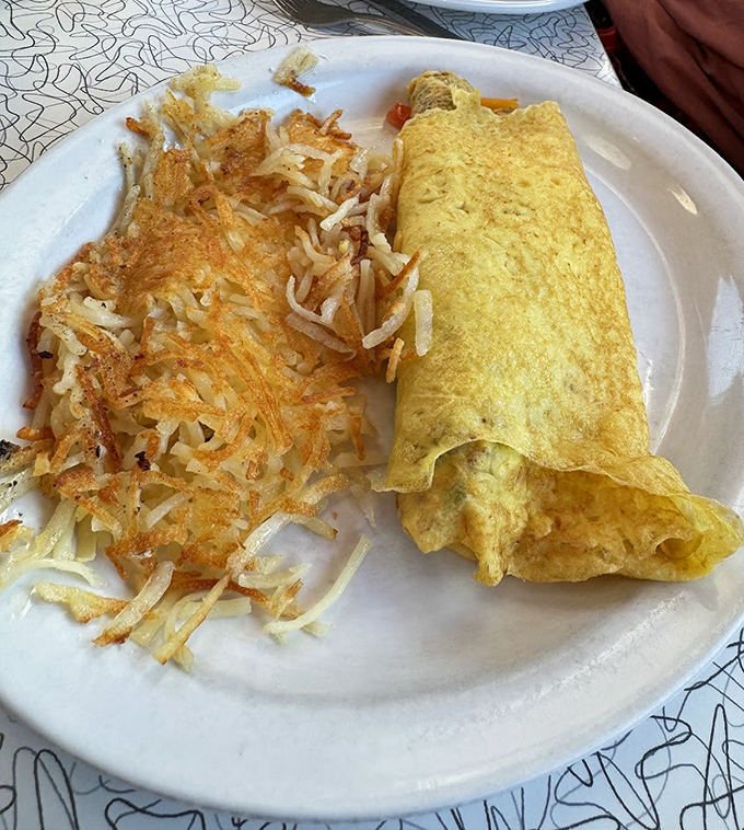 An omelet that clearly graduated with honors from Breakfast University, paired with hash browns that achieved the perfect crisp-to-tender ratio.