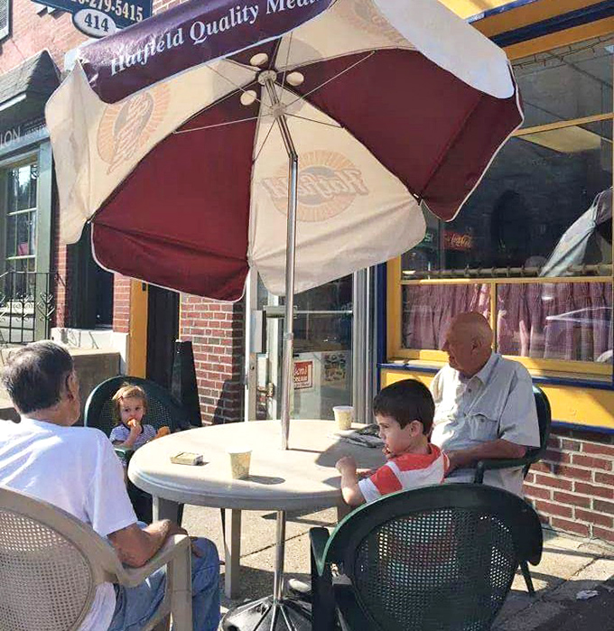Three generations sharing milkshakes and memories. Lou's outdoor seating area proves good food is the universal language across all ages.