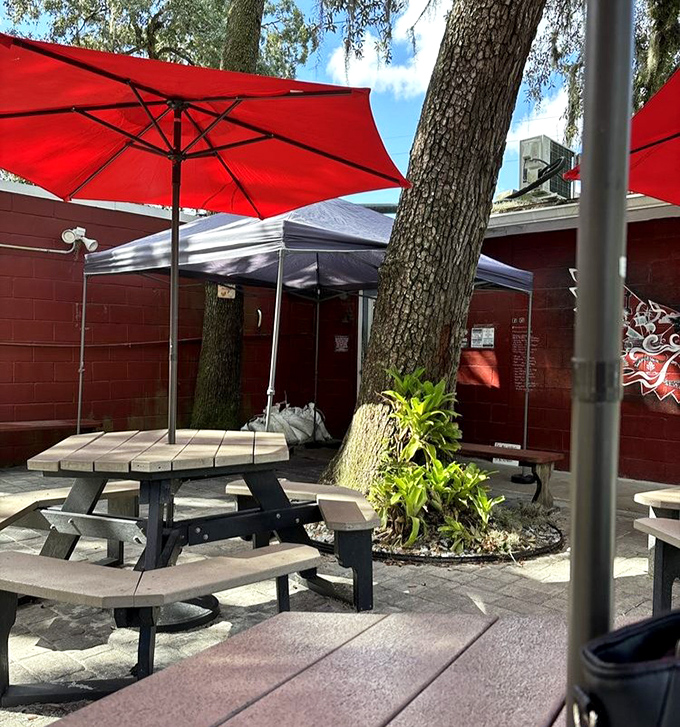 Outdoor dining under oak trees and red umbrellas &ndash; nature's perfect setting for consuming smoked meats while contemplating life's greatest pleasures.