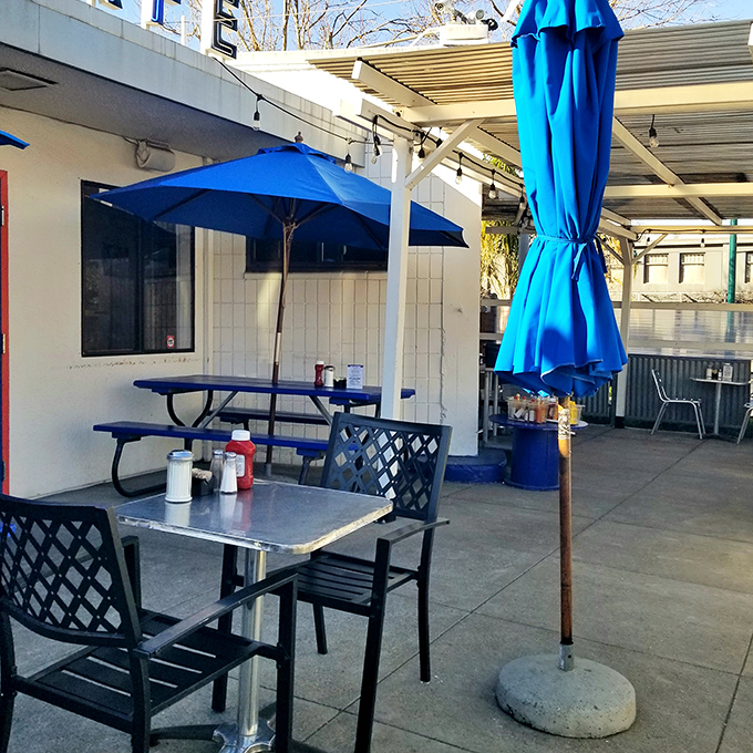 The outdoor seating area&mdash;where the blue umbrellas match the California sky and ketchup bottles stand ready for whatever comes next.