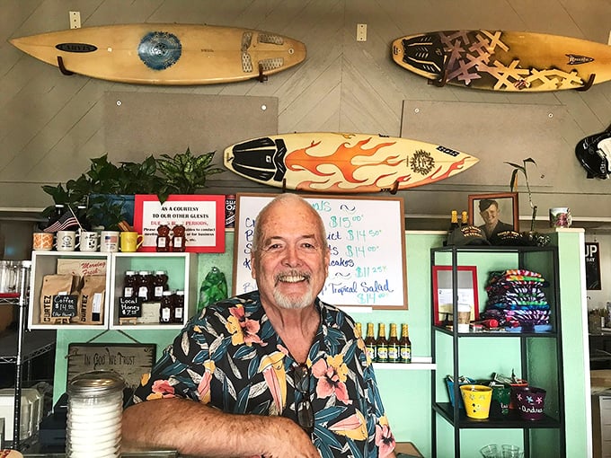 A welcoming smile that says, "Yes, we have the breakfast you've been dreaming about," framed by surfboards that somehow make perfect sense here.
