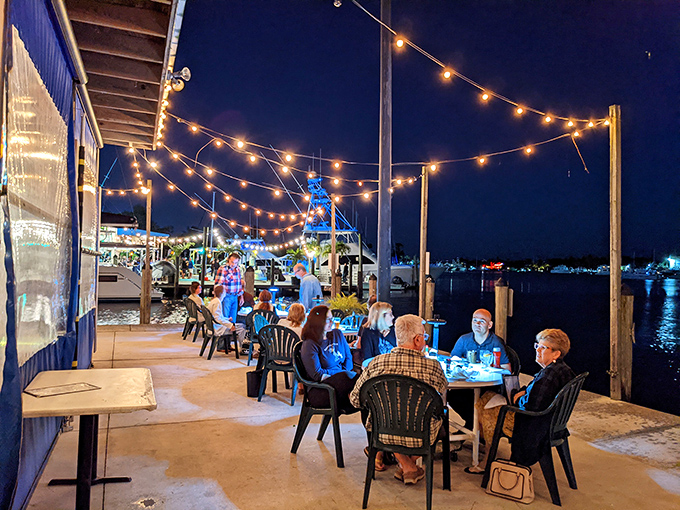 As evening falls, the string lights transform the waterfront patio into a magical dining experience that rivals any five-star view.