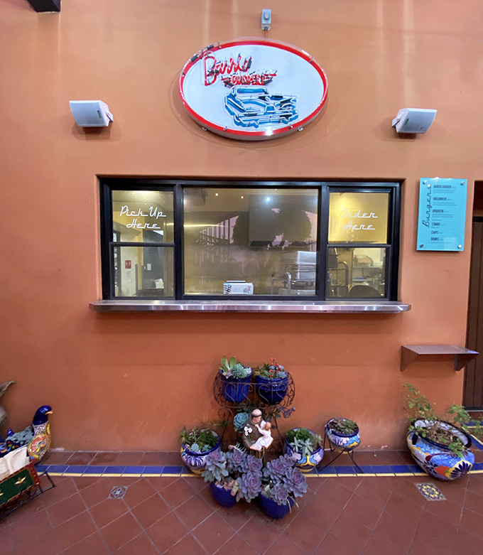 The pick-up window, where dreams come true in paper bags. "Order Here" signs have never promised such delicious fulfillment.