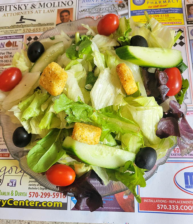 Even the salad looks happy to be here, dressed in its Sunday best with olives, tomatoes, and croutons playing supporting roles.