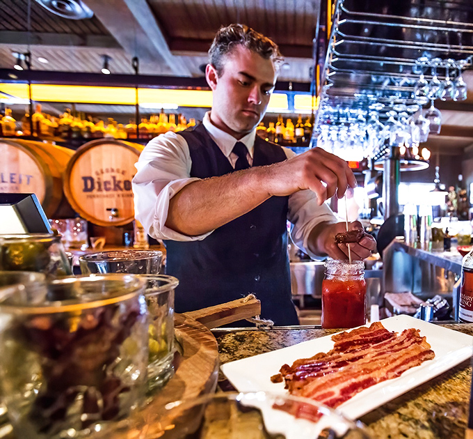 Cocktail craftsmanship in action&mdash;where precision meets showmanship and bacon somehow makes perfect sense as a garnish.