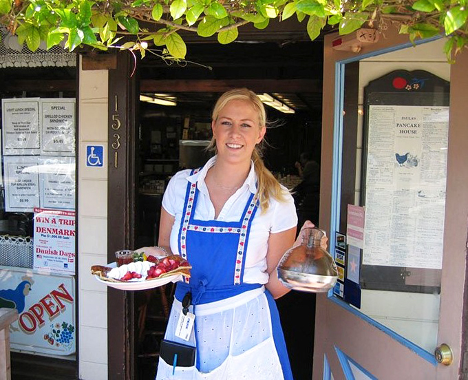 The front counter where breakfast magic begins. Those traditional Danish-inspired aprons aren't just for show&mdash;they're badges of pancake honor.
