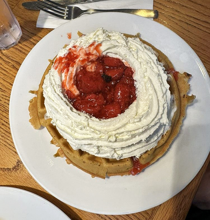 A waffle wearing whipped cream like a couture gown, with strawberries nestled in the center like rubies. Breakfast or dessert? Yes.
