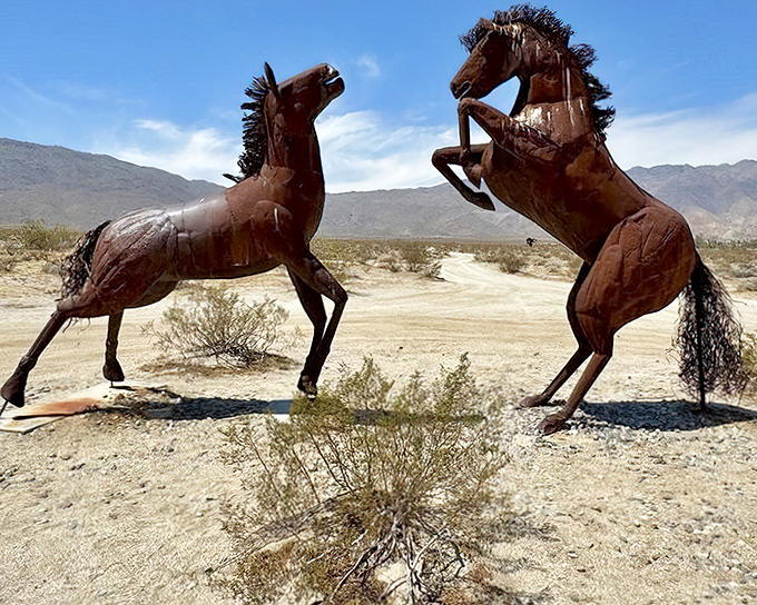 Two wild horses rear dramatically against the desert sky, their metal manes seemingly caught in an eternal desert breeze.