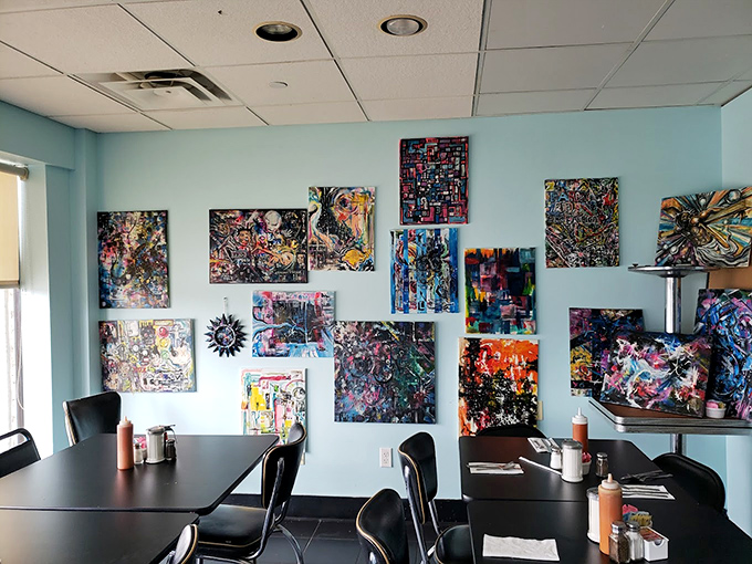 Vibrant local artwork transforms simple blue walls into a community gallery, proving good taste extends beyond just the kitchen.