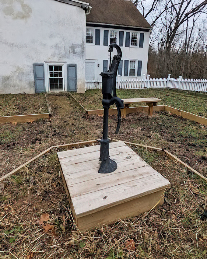 An antique water pump stands sentinel beside the historic homestead. Instant appreciation for modern plumbing, delivered with a dash of colonial charm.