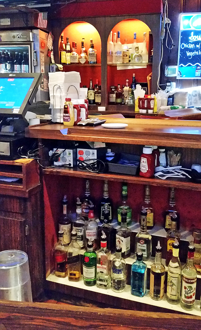 The bar setup speaks volumes: no pretentious mixology, just honest pours and bottles that promise reliable liquid companionship.