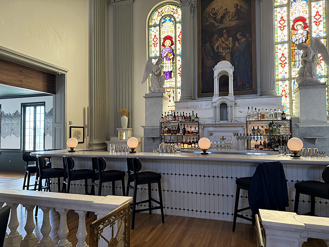 The bar area showcases stunning stained glass windows, where spirits are served beneath windows of spiritual significance.