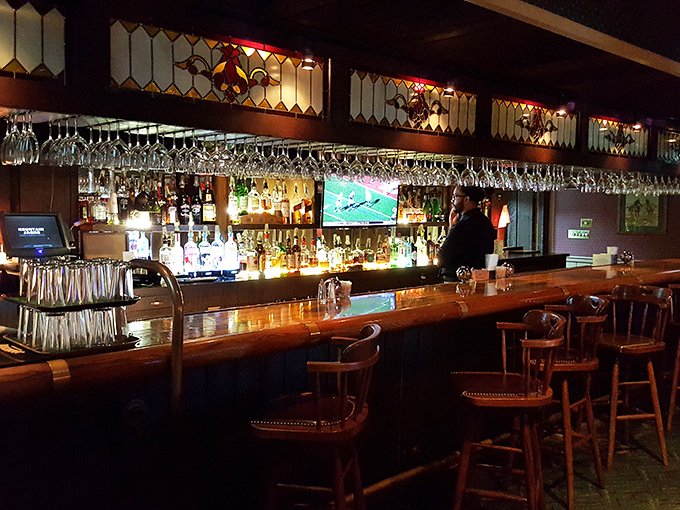 The bar at Mountain Jack's: where stained glass meets sports TV in a wood-paneled paradise of potential poor decisions.