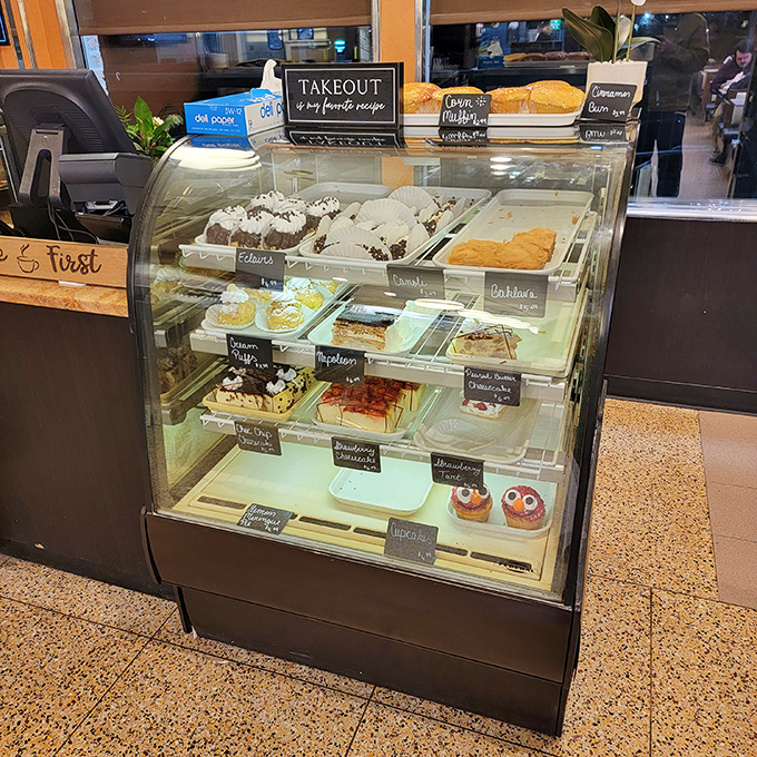 The dessert case stands as a glass-enclosed temple of temptation, where willpower goes to die a deliciously sweet death.