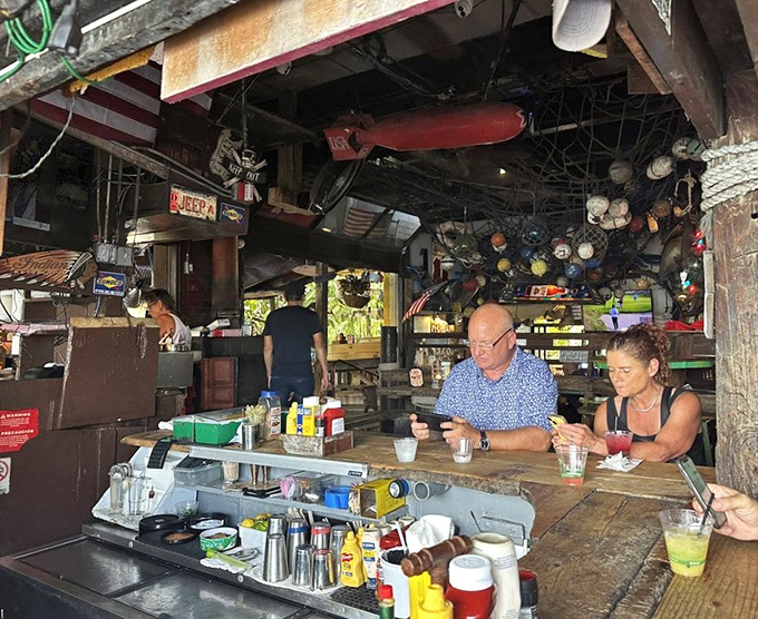 The bar area buzzes with friendly conversation while maritime artifacts create an atmosphere money simply cannot buy.